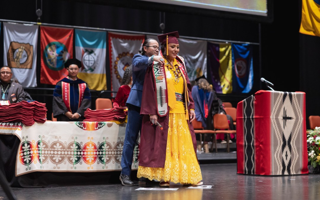 Hundreds of Navajo Sun Devils walk across the stage, encouraged to keep ...